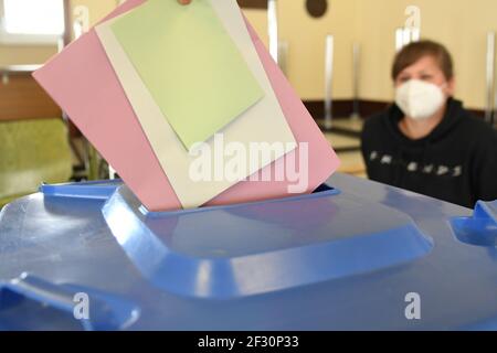 Albshausen, Germany. 14th Mar, 2021. Watched by an election worker, a ...