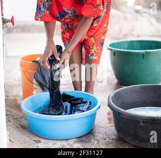 African american woman washing clothes holding detergent bag at laundry ...