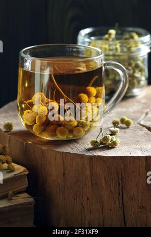 Cup of tea with tansy and tansy flowers on a wooden table. Healing ...