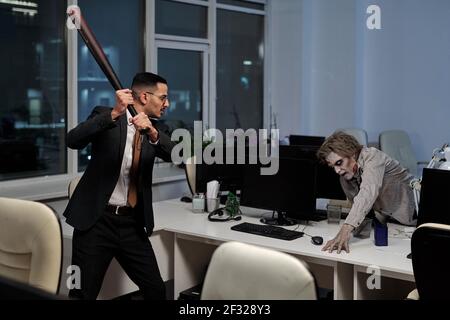 Young spooky businessman with zombie greasepaint on face and hands ...