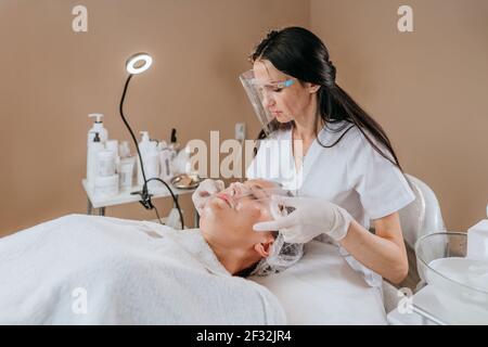 Esthetician or facialist making facial cleansing procedure to a woman ...