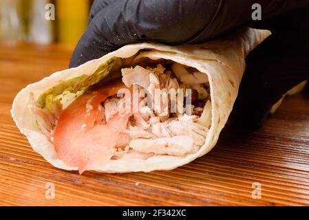 Burrito making process. The chef wraps stuffed pita on a wooden table ...