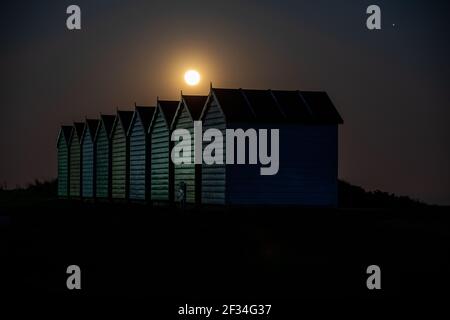 The rising moon seen above beach huts in Rustington, West Sussex Stock ...