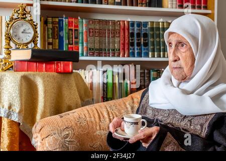 Happy aged muslim woman drinking water, holding glass and smiling at ...