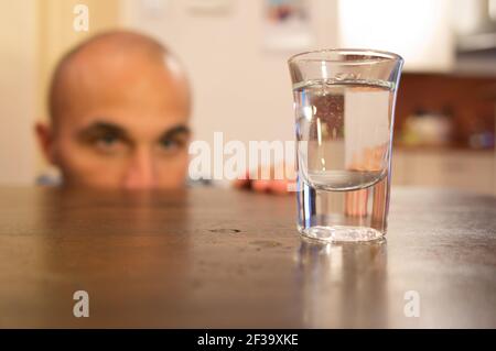Addicted man looking at a glass filled with alcohol Stock Photo - Alamy
