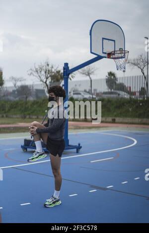 Young male bodybuilder standing knee bend, one leg squat, showing front ...
