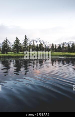 A beautiful lake surrounded by snowy mountains against a cloudy sky ...