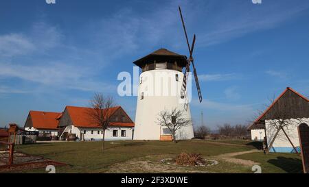 Folklore colony with an old windmill with blue sky above Stock Photo ...
