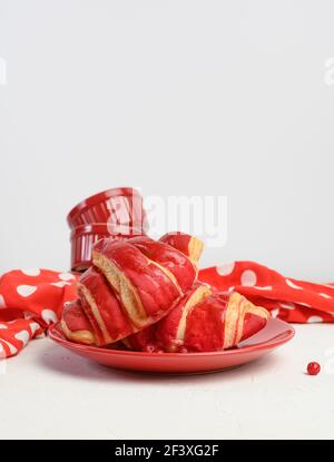 two baked croissants with cherry glaze on a red ceramic plate, white ...
