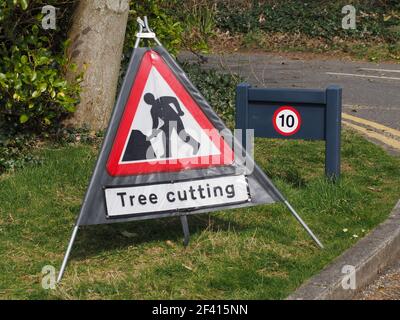 Red and white tree cutting warning sign standing at side of road with ...
