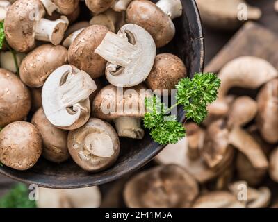 Different brown colored edible mushrooms on black table with herbs. Top ...