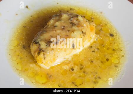 A tasty hake loin in green sauce on a white plate. Fish and healthy ...
