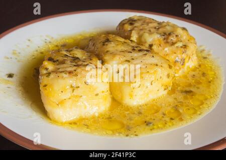 A tasty hake loin in green sauce on a white plate. Fish and healthy ...