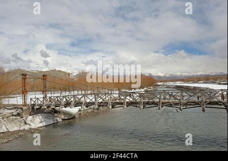 Old wooden suspension bridge across small river in Upper Modi Khola ...