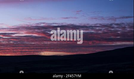 Dramatic, blazing sunset over snow covered hills and mountains ...