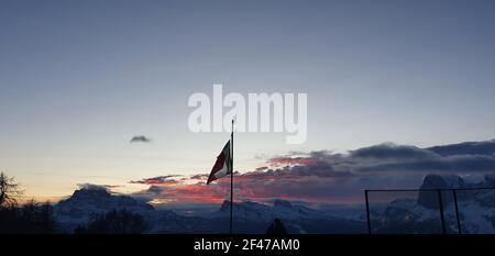 the Italian flag flutters as the sun sets with colored clouds Stock ...