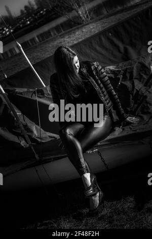 A grayscale shot of a Caucasian woman wearing a dress posing in a wild ...