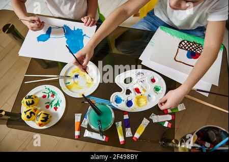 Hands of a family drawing with pencil and paints. Top view to white ...