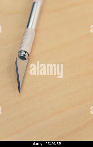 A vertical shot of the metallic scalpel on a plywood surface isolated ...