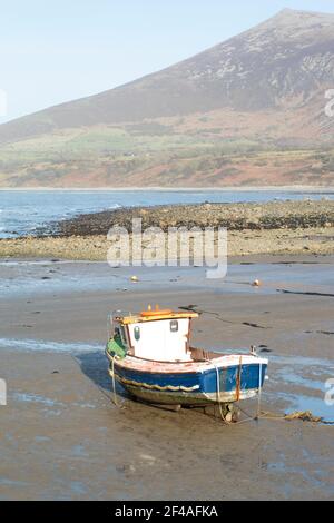 A vertical shot of a small boat on the beach with sea and cloudy blue ...