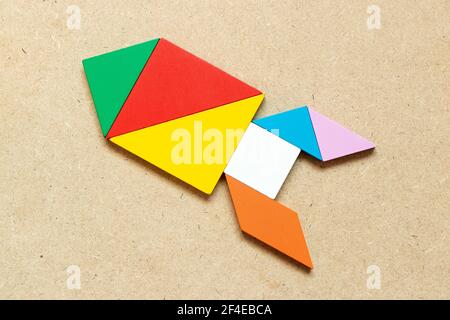 Color tangram puzzle in missile or rocket shape on wood background ...