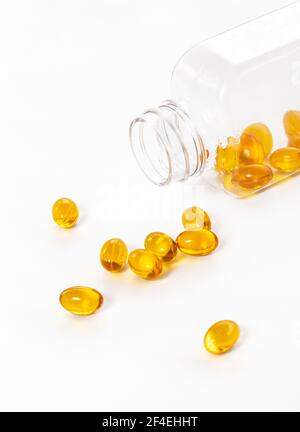 Yellow color fish oil capsules with glass bottle on white background ...
