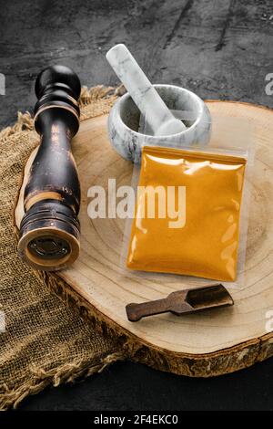 Wooden cross section with turmeric in plastic package and mortar and ...