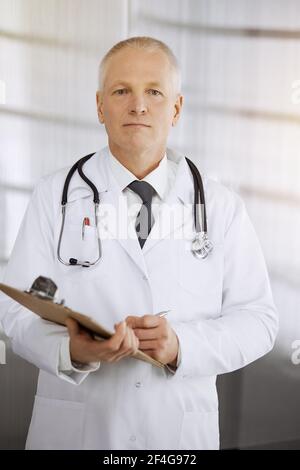 Friendly man-doctor standing straight and showing Ok sign in clinic ...