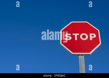 Vertical traffic stop sign, in red and white tones, on blue background ...