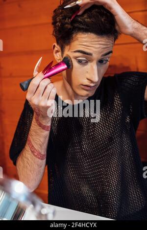 Transsexual applying makeup on his face in the morning and preparing ...
