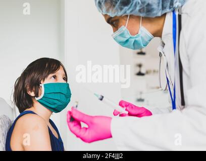 Little cute child with mask getting injection Stock Photo - Alamy