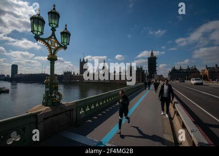 People walk along Westminster Bridge in London wearing face coverings ...