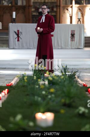Reverend Canon Andrew Trenier holds a candle next to a green meadow ...