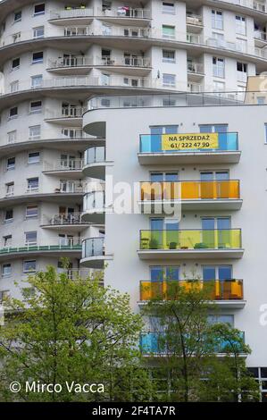 POZNAN, POLAND - Apr 26, 2015: Many trees and a green grass field in front of a high apartment ...