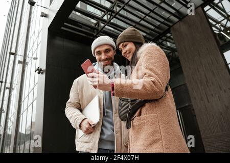 low angle view of freelancers in beanie hats waving hands while having ...
