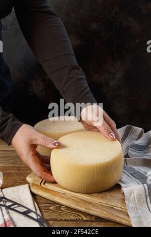 Somebody hands put a piece of fresh homemade cheese on a wooden board ...