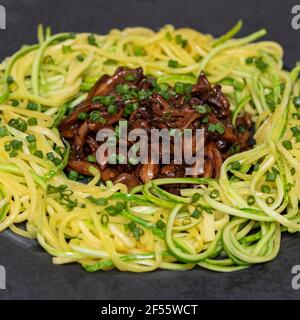 Zucchini spaghetti with shimeji on black stone plate Stock Photo - Alamy