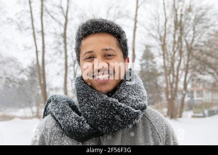 Black man with scarf around neck using nasal spray while sitting on bed ...