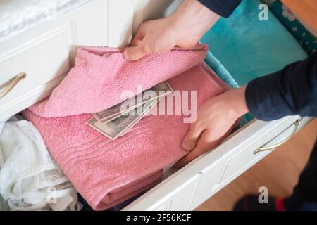 hand taking hidden stash of cash money from the wardrobe at home Stock ...