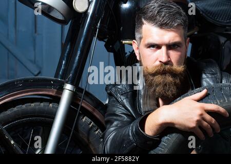 Bearded biker in leather jacket poses on chopper in city, front view ...