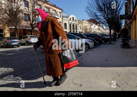 A woman wears a mask while walking under a cherry blossom tree in ...