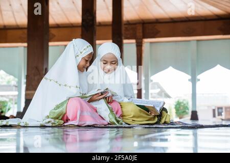 two Asian Muslim girls reading and studying the holy book of the Al ...