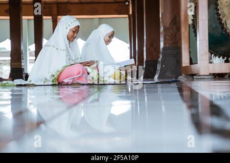 two Asian Muslim girls reading and studying the holy book of the Al ...