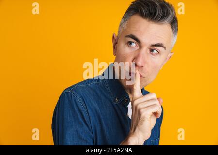 Serious handsome man showing silence gesture at camera isolated over ...