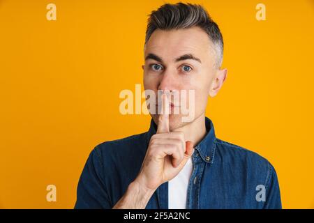 Serious handsome man showing silence gesture at camera isolated over ...