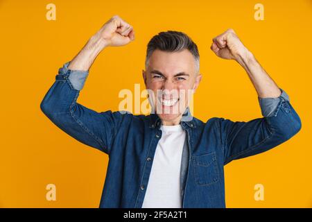 Excited handsome man exclaiming and showing winner gesture isolated ...