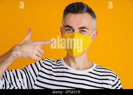 Joyful handsome man in protective mask looking at camera isolated over ...