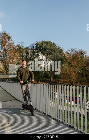 young strong man riding electric kick scooter copy space Stock Photo ...