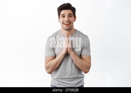 Thank you gesture. Handsome grateful man holding hands near heart pink ...