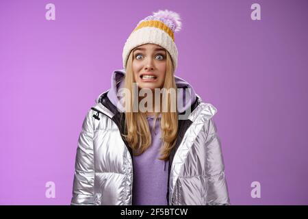 Awkward worried cute timid blond girl in silver jacket hoodie winter ...